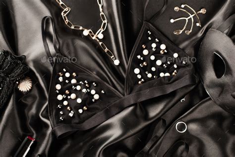 Top View Of Bra Sexual Mask And Accessories On Black Satin Background