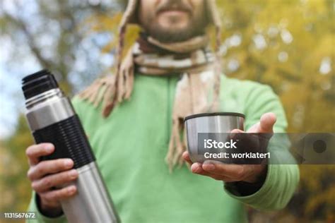 니트 모자와 스카프에 남자 미소와 함께 뜨거운 음료보온병에서 차 또는 커피를 제공 전면 보기 가을에 대한 스톡 사진 및 기타