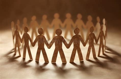 Hands Holding Cutout Silhouettes Of Human Figures Representing Teamwork