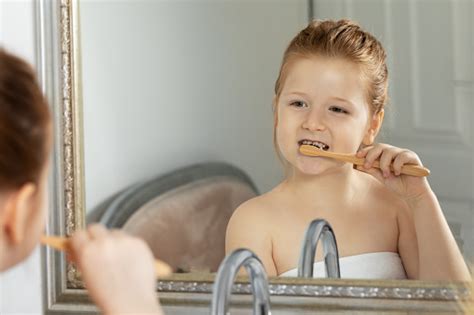 작은 아름다운 소녀는 환경 친화적 인 재료로 만든 칫솔로 거울 앞 욕실에서 그녀의 이빨을 닦고 매일 위생 절차를 수행 6 7 살에 대한 스톡 사진 및 기타 이미지 Istock