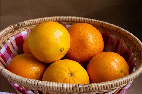 밝은 갈색 배경에 체크 무늬 천이 있는 고리 버들 바구니에 잘 익은 오렌지 0명에 대한 스톡 사진 및 기타 이미지 0명 감귤류 과일 건강한 식생활 Istock