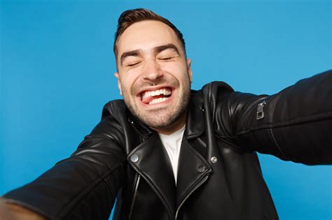 까만 가죽 자 켓 흰색 T셔츠 파란색 벽 배경 스튜디오 초상화에 고립 된 찾고 세련 된 젊은 얼굴을 가진 남자의 셀 카를 닫습니다 사람들은 진지한 감정 개념입니다 복사