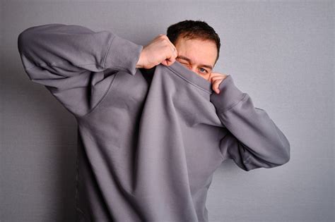 남자는 회색 스웨트셔츠를 입고 밝은 벽 근처에서 포즈를 취한다 제스처 감정 캐주얼 직장에서 스튜디오 모델입니다 비문과 로고를 위한 장소 후드티에 대한 스톡 사진 및 기타