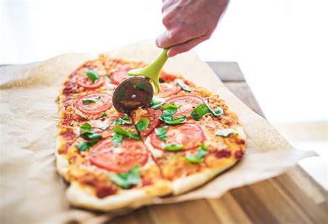 피자 커터를 사용하여 토마토와 바질로 맛있는 수제 피자를 손으로 자르기 나폴리 피자에 대한 스톡 사진 및 기타 이미지 나폴리 피자 독일 마르가리타 Istock
