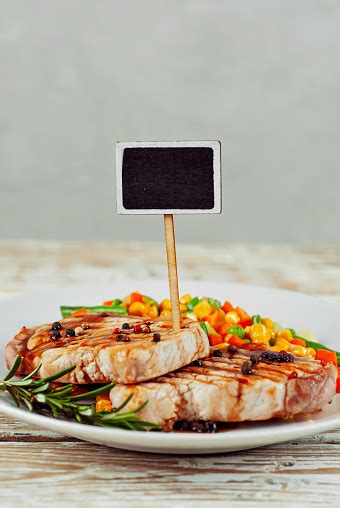 구운 고기 조각 흰색 접시에 야채와 스테이크 스테이크 근처의 옥수수 당근 녹색 완두콩 샐러드 플레이트 근처의 텍스트를 위한 공간과 여유 공간을 복사합니다 고기에 비문 접시