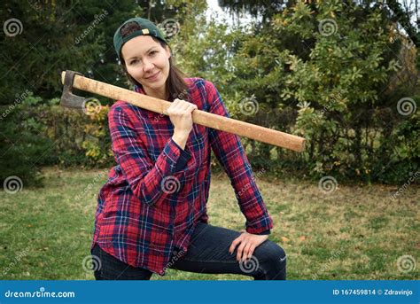 Smiling Female Lumberjack Holding A Huge Axe On Her Shoulder Stock