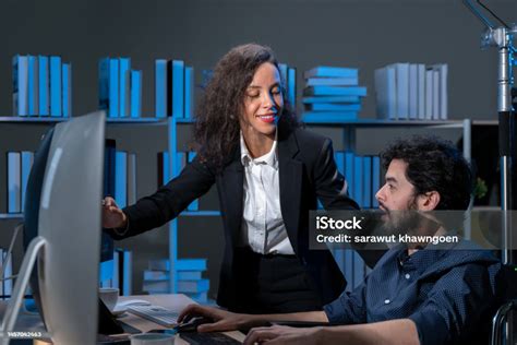 열심히 일하는 비즈니스 남녀 설정된 목표에 따라 작업을 완료하기 위해 밤늦게까지 일하기 두 사람은 회사의 재무 그래프를주의 깊게 살펴 보았습니다 2명에 대한 스톡 사진 및