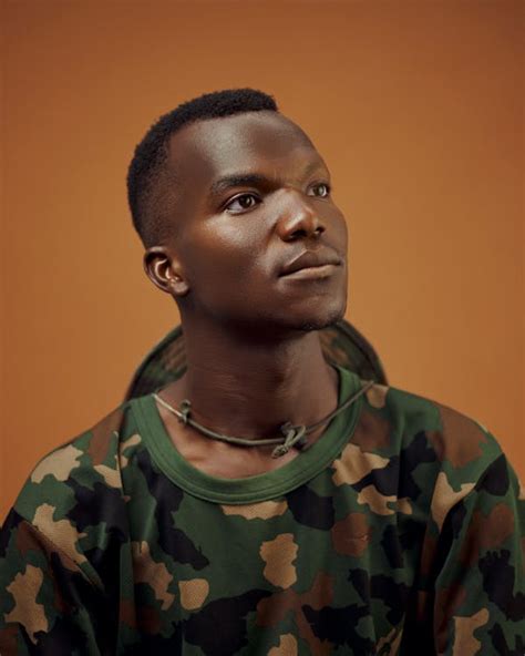 주황색 배경에 위장 셔츠를 입은 남자의 초상화 · 무료 스톡 사진