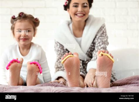 Cute Daughter With Mother Making Pedicure And Curling Hair At Home