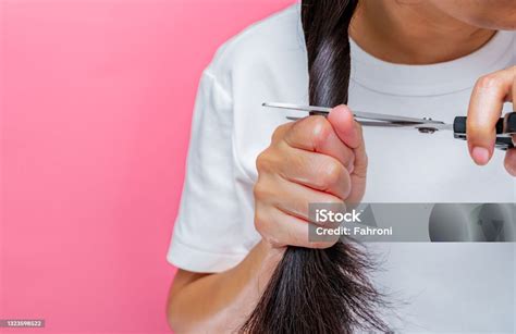 손상되고 건조한 모발을 자르는 여성 암 환자에게 기부를 위한 가위로 머리를 자르는 아시아 여자 유방암 을 위한 모발 기부 분홍색 배경에 검은 긴 머리를 가진 여자 기부함에