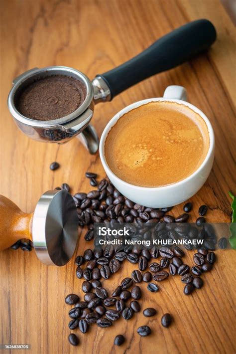 에스프레소 커피 컵과 바리스타 커피 도구 포터필터의 상위 뷰 탬퍼와 나무 테이블에 녹색 커피 잎이 있는 다크 로스팅 커피 원두 0명에 대한 스톡 사진 및 기타 이미지