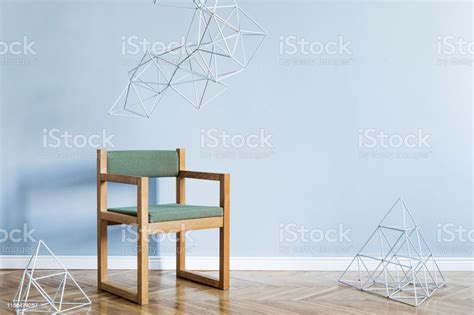 디자인 녹색 안락 의자 삼각형 기하학적 조각과 열린 공간의 미니멀하고 현대적인 인테리어 회색 배경 벽 갈색 나무 마루 방의