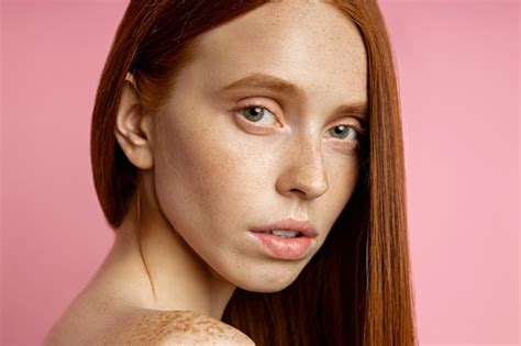 주근깨 붉은 머리 깨끗한 피부 벌거벗은 어깨를 가진 진지한 백인 여성 모델의 얼굴 클로즈업 초상화는 화장 없이 차분한 표정으로 카메라를 쳐다보고 있습니다 자연의