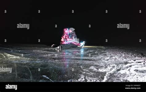 Young Loving Couple Skating At Ice Rink At Night Man And Woman Kiss Hug Have Fun Learn To