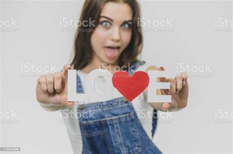 젊은 아름 다운 소녀는 회색 배경에 있습니다 데님 수트와 화이트 티셔츠를 입고 사랑의 말씀으로 표지판을 들고 있다 T 셔츠에 대한 스톡 사진 및 기타 이미지 Istock