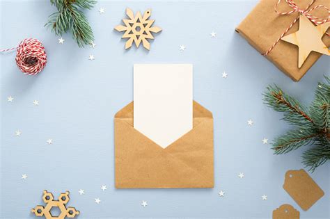 색종이 스타 선물 상자 나무 눈송이 전나무 나무 가지로 장식 파스텔 블루 배경에 크래프트 종이 봉투에 빈 카드 크리스마스 새해 겨울 휴가 초대 모형 0명에 대한 스톡 사진