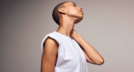 Androgynous Female With Shaved Head Standing Against Colored Background