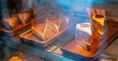 젊은 아시아 여성 커피숍 직원이 카페에서 베이커리 냉장고 쇼케이스에 페이스트리와 케이크를 배치하고 있다 고객에게 서비스를 제공하기 위해 레스토랑을 준비하는 여성 웨이트리스