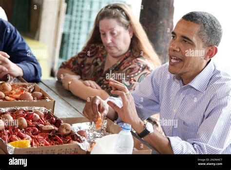President Barack Obama Eats A Shrimp As He Sits Next To Convenience Store Owner Patti Rigaud As