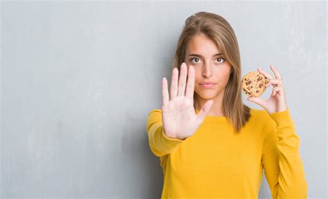 초콜릿을 먹는 그런 지 회색 벽에 아름 다운 젊은 여 자가 심각 하 고 자신감 표현 정지 표시를 하 고 오픈 손으로 과자 칩 제스처를 방어 경계 표지에 대한 스톡 사진 및