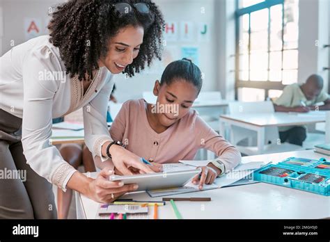 Female Teacher Helping Young Girl Teaching Creative Work In Book And