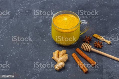 전통적인 인도 음료 심황 우유는 심 황과 뿌리 생강 계피 어두운 배경에 아니스 별 유리 머그잔에 황금 우유입니다 체중 감량