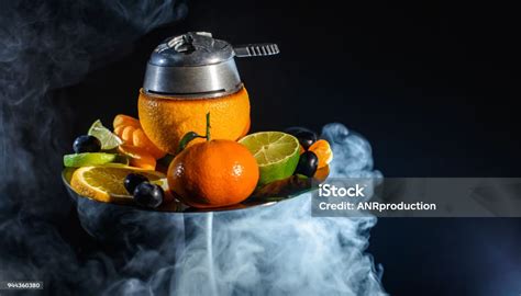 현대 과일 오렌지와 레드 Kaloud와 신선한 과일을 많이 물 담 뱃 대 그릇 핫 코코넛 석탄 격리 검정색 배경에서 연기의 많은 숯불 어두운 Shisha 라운지에 흡연