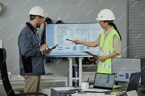 Premium Photo Two Engineers Reviewing Blueprints Indoors And Pointing