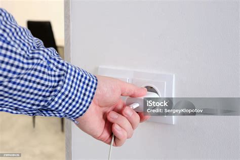 클로즈업된 한 남자가 스마트폰 충전기를 들고 거실의 소켓에 꽂고 있다 Brand Name Smart Phone에 대한 스톡 사진 및 기타 이미지 Brand Name