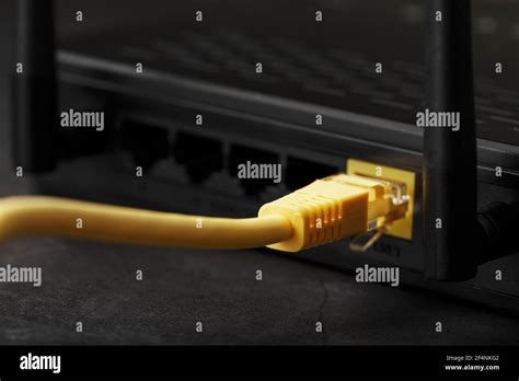 Wireless Modem Router With Yellow Cable And Lan Port For Connection On A Black Background