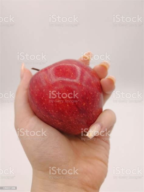 긴 매큐징 손톱 을 가진 젊은 여성의 손은 빛 배경에 잘 익은 빨간 줄무늬 사과를 들고 있습니다 건강한 식습관의 개념 베이비 붐