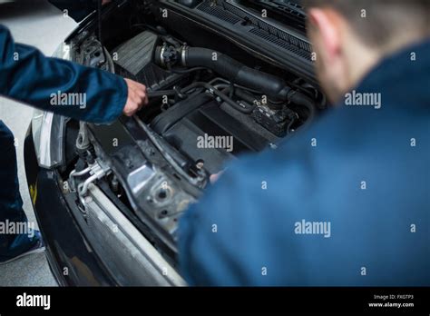 Mechanics examining car engine Stock Photo - Alamy