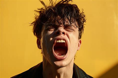 Visual Young Man Yelling In Front Of A Yellow Background Premium Ai