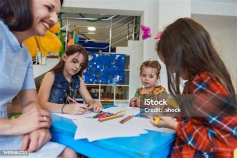 보육원에서 미술 수업을하거나 여성 교사와 함께 초등학교 교실에서 그림을 그리는 동안 창조적 인 아이들 고등학교 이하에 대한 스톡