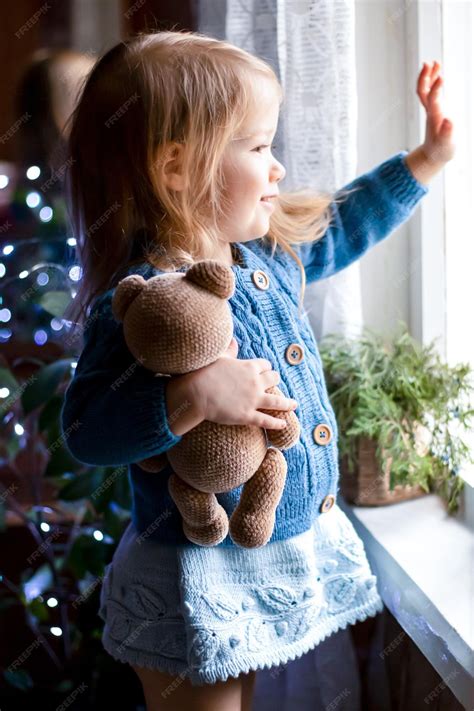 Premium Photo Cute Little Blonde Girl In Blue Clothes With Toy Teddy