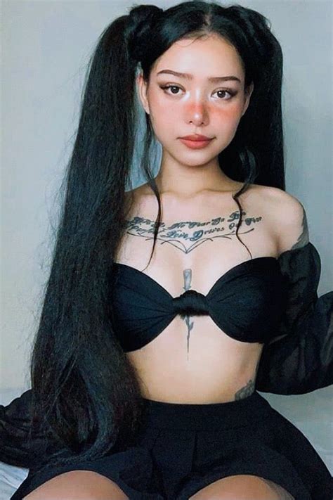 A Woman With Long Black Hair And Tattoos On Her Chest