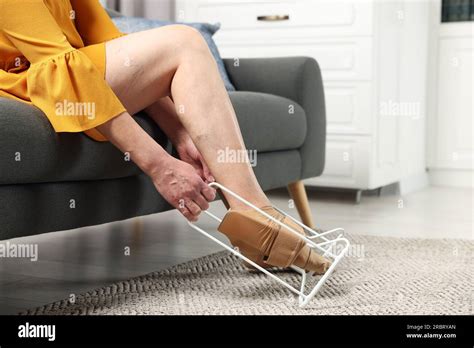 Woman Putting On Compression Tights With Stocking Donner In Living Room Closeup Prevention Of