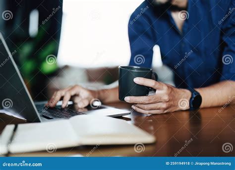 Portrait Of An Asian Man Working On A Computer And Drinking Coffee