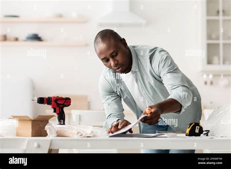 Concentrated African American Man Reading Furniture Installation Instruction Assembling Kitchen
