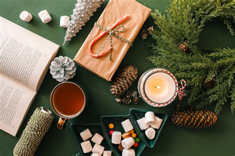 녹색 배경에 사탕 지팡이 불을 붙인 양초 차 펼쳐진 책 솔방울 마시멜로 상록 가지로 포장된 선물을 특징으로 하는 아늑한 크리스마스 설정 감정에 대한 스톡 사진 및 기타