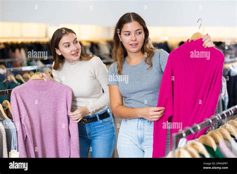 Portrait Of Two Positive Women Choosing Cardigan In Clothing Shop Stock