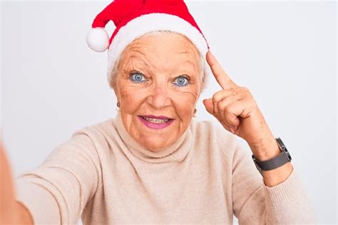 Crhistmas 산타 모자를 착용 회색 머리 여자는 손과 손가락으로 가리키는 고립 된 흰색 배경을 통해 셀카를 매우 행복 12월에 대한 스톡 사진 및 기타 이미지 Istock
