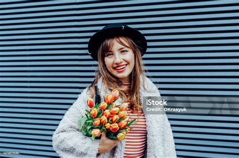 회색 줄무늬 벽 배경에 신선한 튤립 꽃을 잔뜩 들고 있는 행복하고 젊은 웃는 패션 여성의 초상화 도시 도시 거리 패션 봄 분위기 선택적 초점 여자에 대한 스톡 사진 및 기타