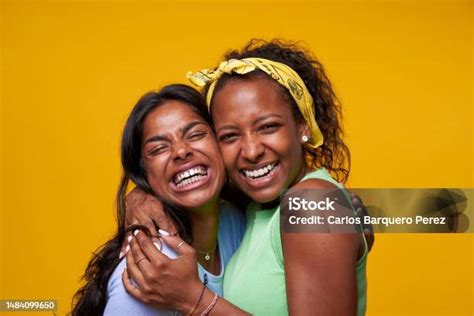 Two Beautiful Black Girls Hugging Smiling Isolated On Yellow Background