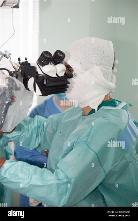 A Neurosurgeon Doctor Looks Into A Microscope During An Operation