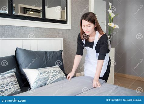 Young Maid Tidying Up Bed In Hotel Room Cleaning Service Concept Stock