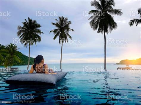 젊은 여 자가 앉아 Beanbag 수영장에서 휴식 및 기대 일몰 시에 바다 근처에 건강한 생활방식에 대한 스톡 사진 및 기타 이미지 건강한 생활방식 관광 관광 리조트