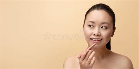 Cheerful Millennial Chinese Naked Woman Applies Pencil To Lips And Makes Basic Nude Makeup Stock