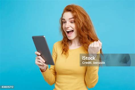 뭔가 각종 디지털 테이블에 웃 고 행복 세로 젊은 아름 다운 매력적인 Redhair 여자를 닫습니다 블루 파스텔 배경입니다 공간에 복사 합니다 귀여운에 대한 스톡 사진 및