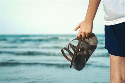 Premium Photo Midsection Of Person Holding Sandals At Beach